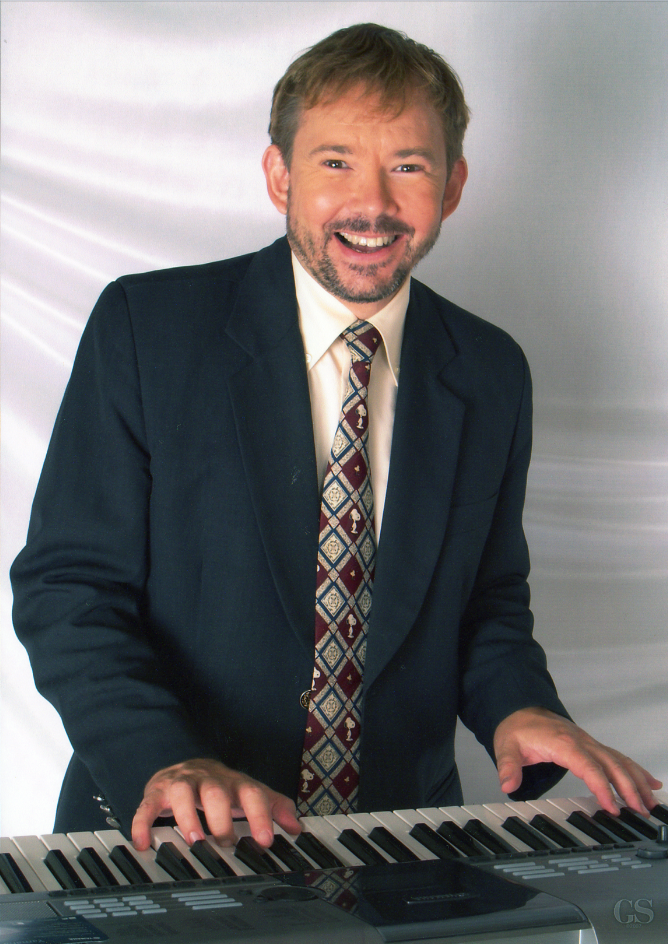 Steve Kuban looking at camera, at small keyboard